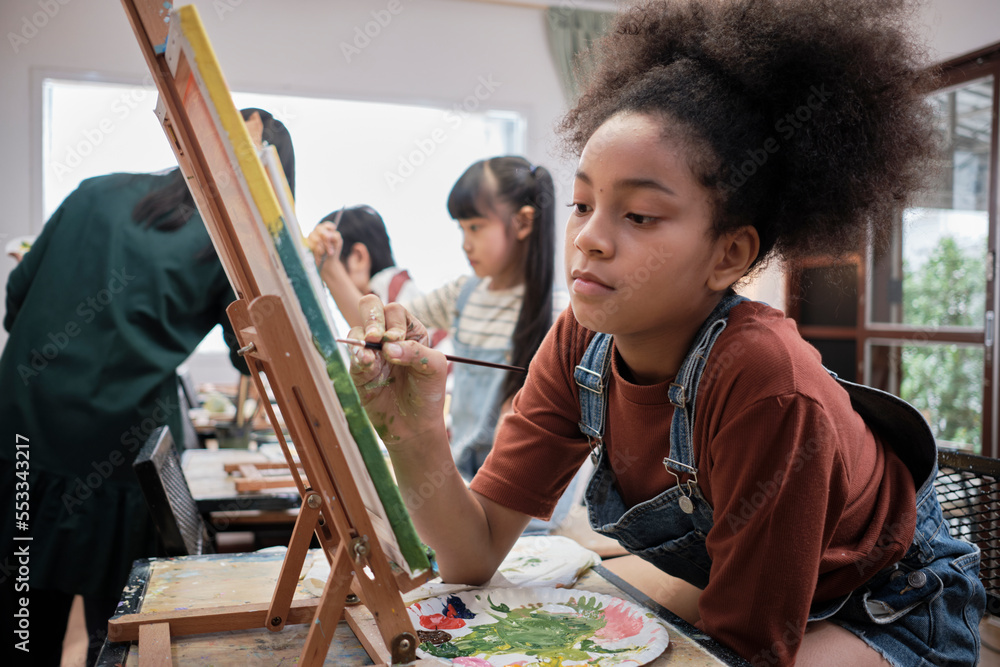 African American girl concentrates on acrylic color picture painting on ...
