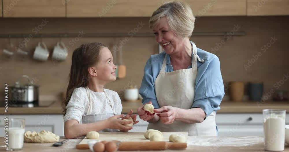 Loving older grandmother teach her cute little 8s granddaughter to cook ...