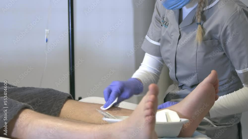 Nurse cleans the leg of a male patient on a hospital bed Stock ビデオ ...
