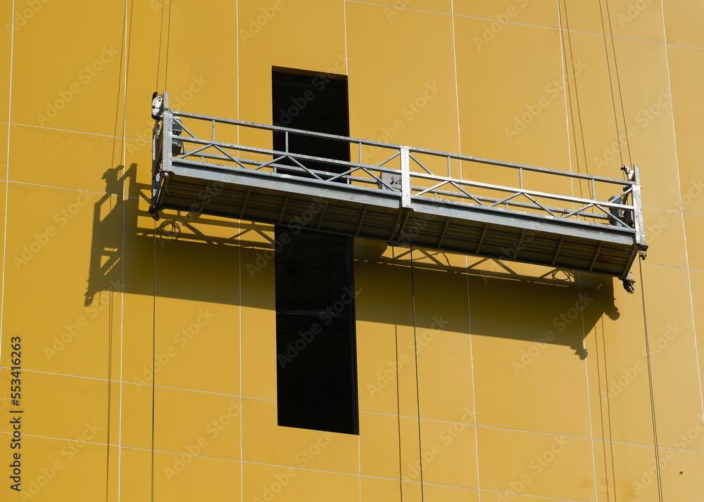 Suspended access cradle against yellow building facade Stock Photo ...