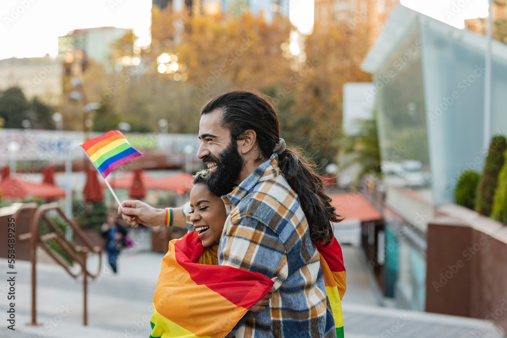 Diverse people walking in the Pride parade with the rainbow flag as a ...