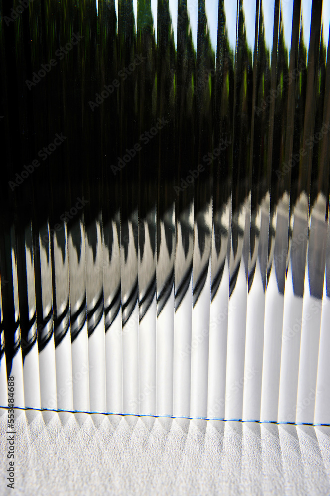 Direct view through vertical stripes of clear corrugated glass creating ...
