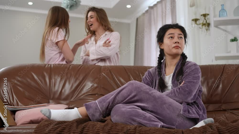 Wide shot sad offended Asian woman sitting on couch with crossed hands ...