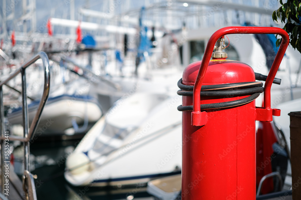 Fire extinguisher close-up on the mooring of the yacht club, blurred ...