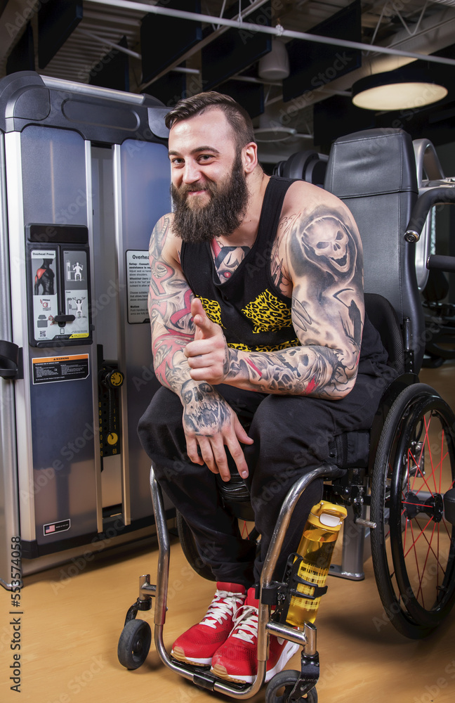 A paraplegic man looking at the camera and giving an affirming hand ...