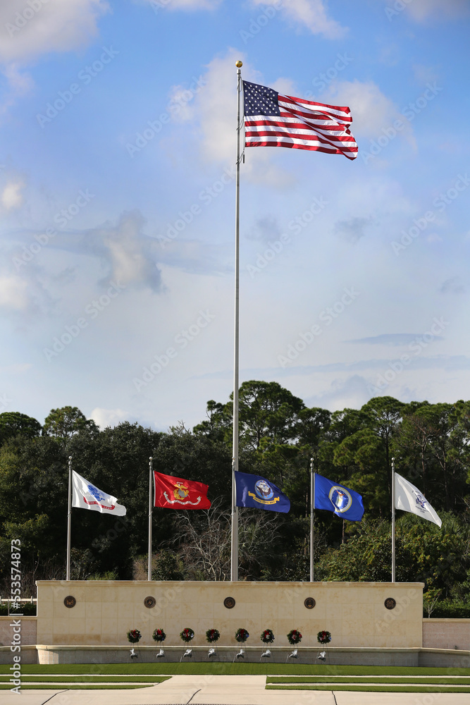 Branches of military flags and American Flag blowing in the wind with ...