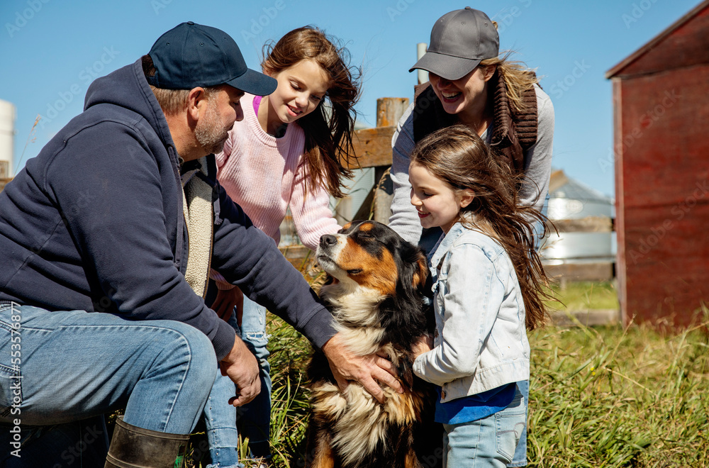 Parents with their two young girls showing their dog affection on their ...