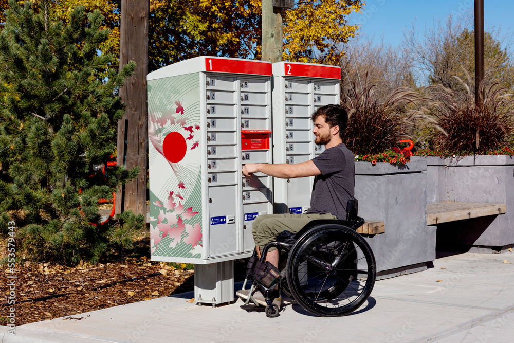 Young paraplegic man at the community mailboxes getting his mail ...