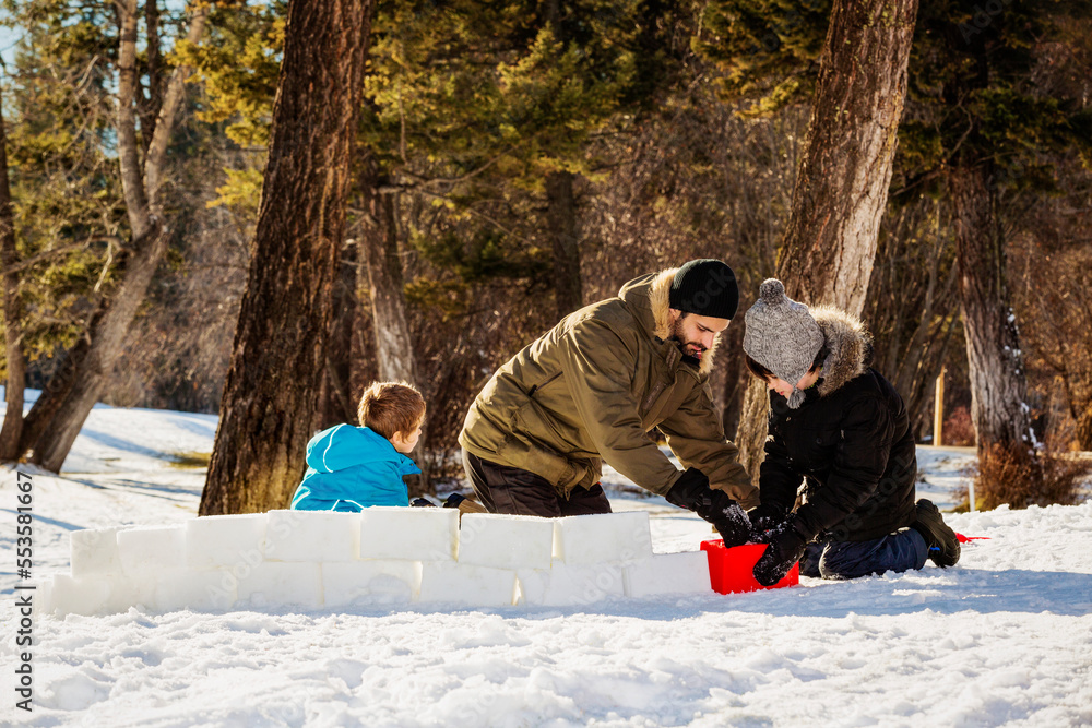 Father And Sons Use A Plastic Mold To Make Snow Blocks For Building An ...