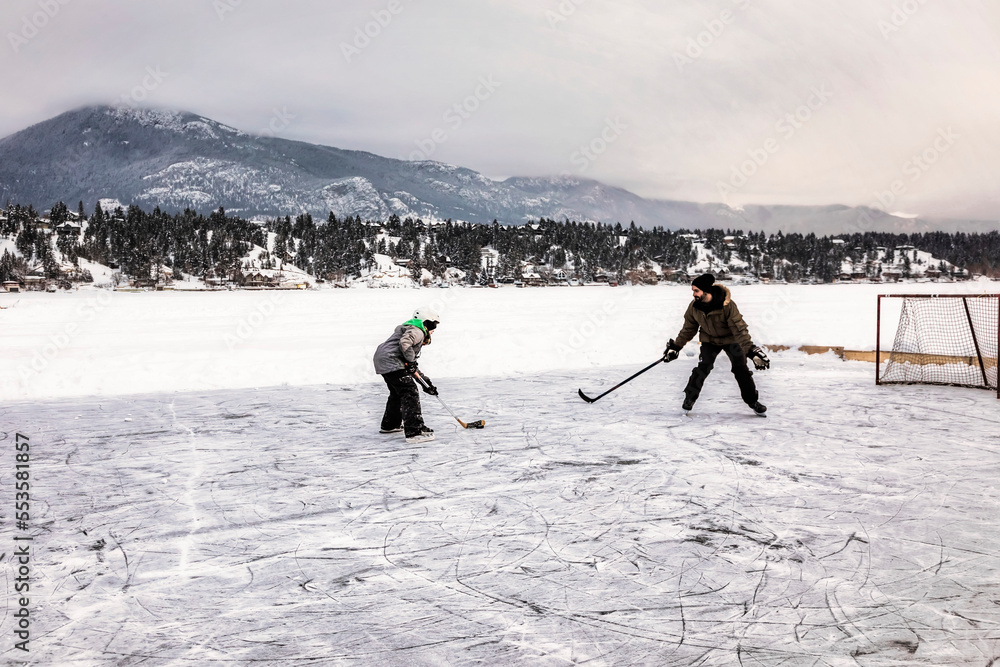 Father and his son playing hockey on a frozen Windermere Lake during ...