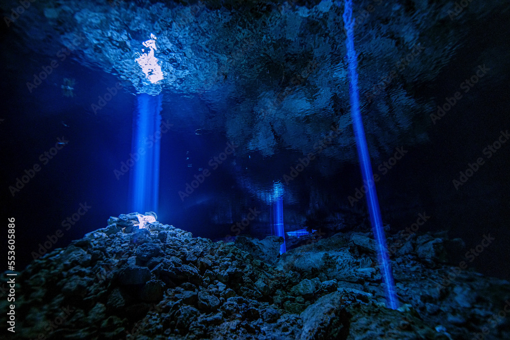 Light rays pass through holes in the cave ceiling in an underwater cave ...