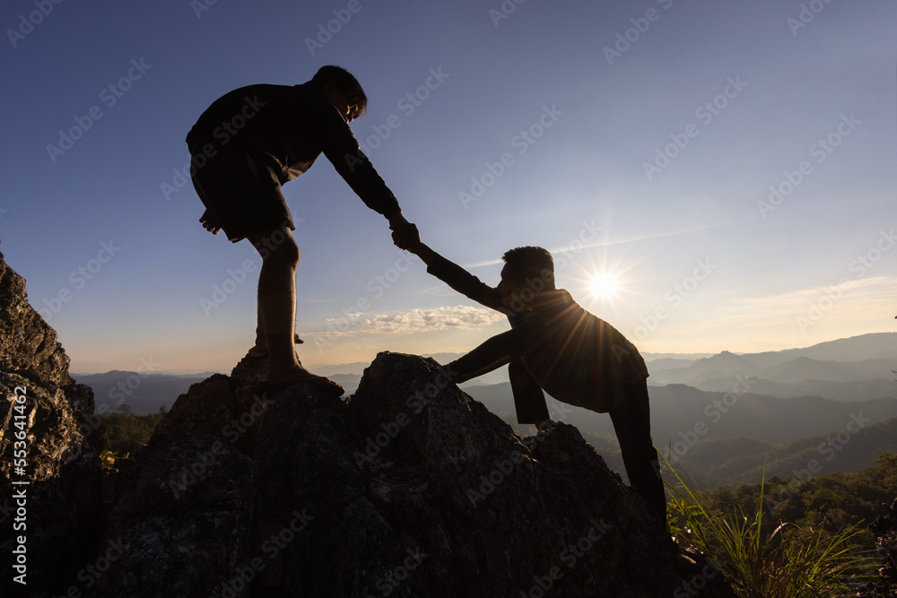 Silhouette of helping hand between two climber. couple hiking help each ...