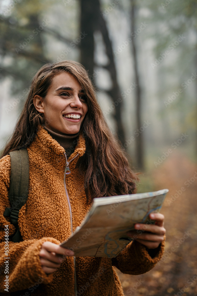 Female explorer spending an autumn day in nature and holding a map for ...