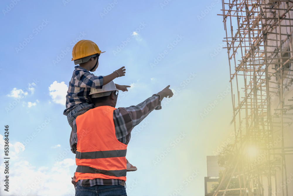 Engineer father carrying son on shoulder pointing at building at ...