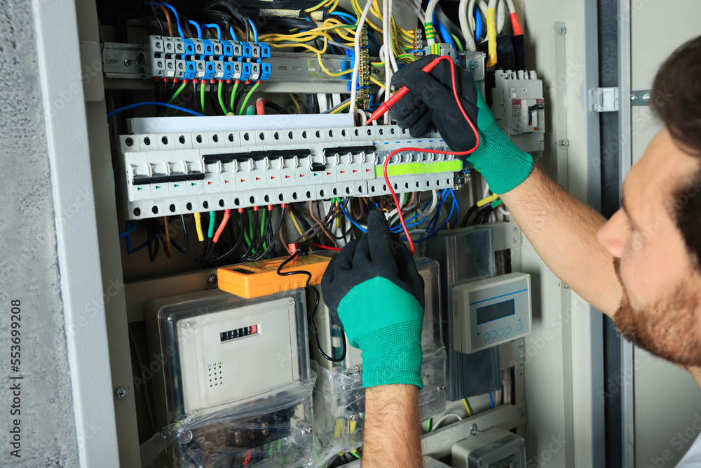 Electrician checking electric current with multimeter indoors, closeup ...