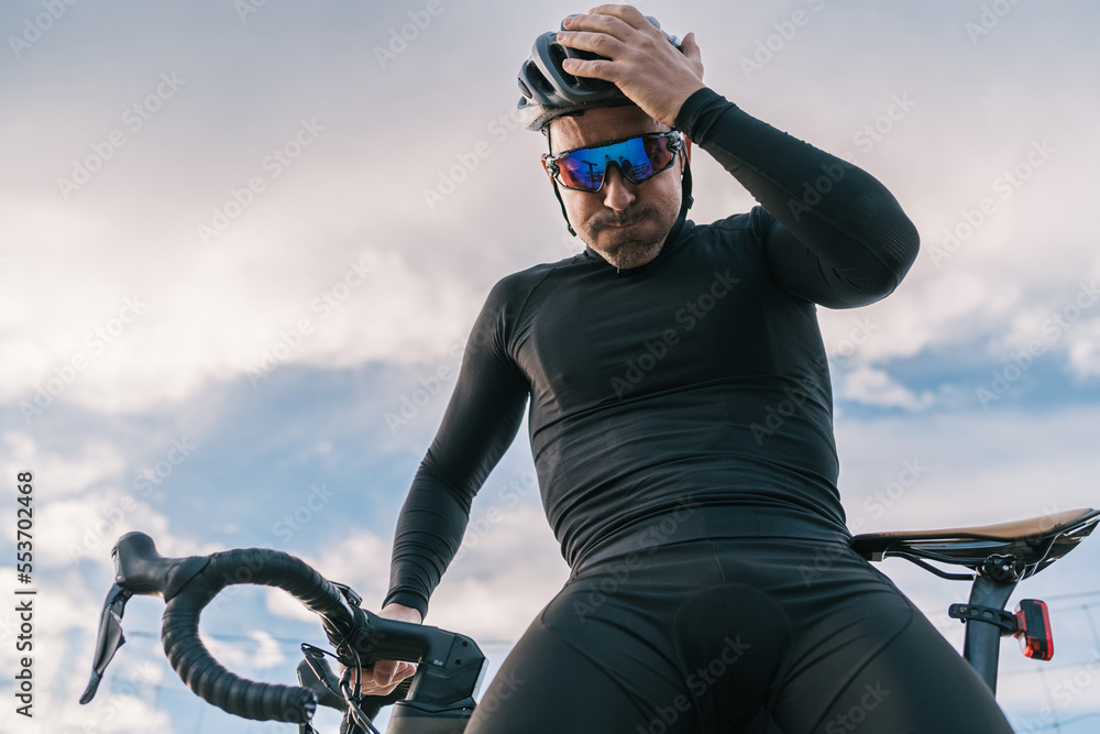 Male cyclist dressed in black sitting on his bicycle, holding his hand ...