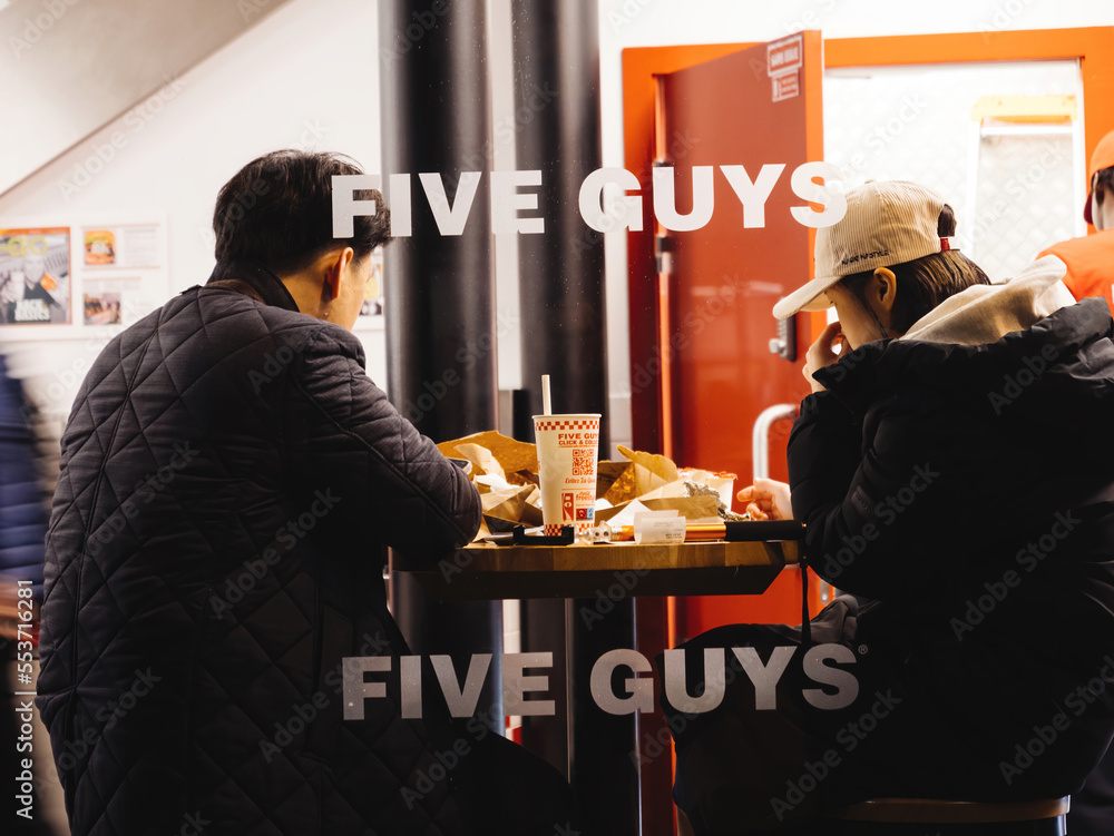 London, United Kingdom - Circa 2022: Male friends eating a t the fast ...