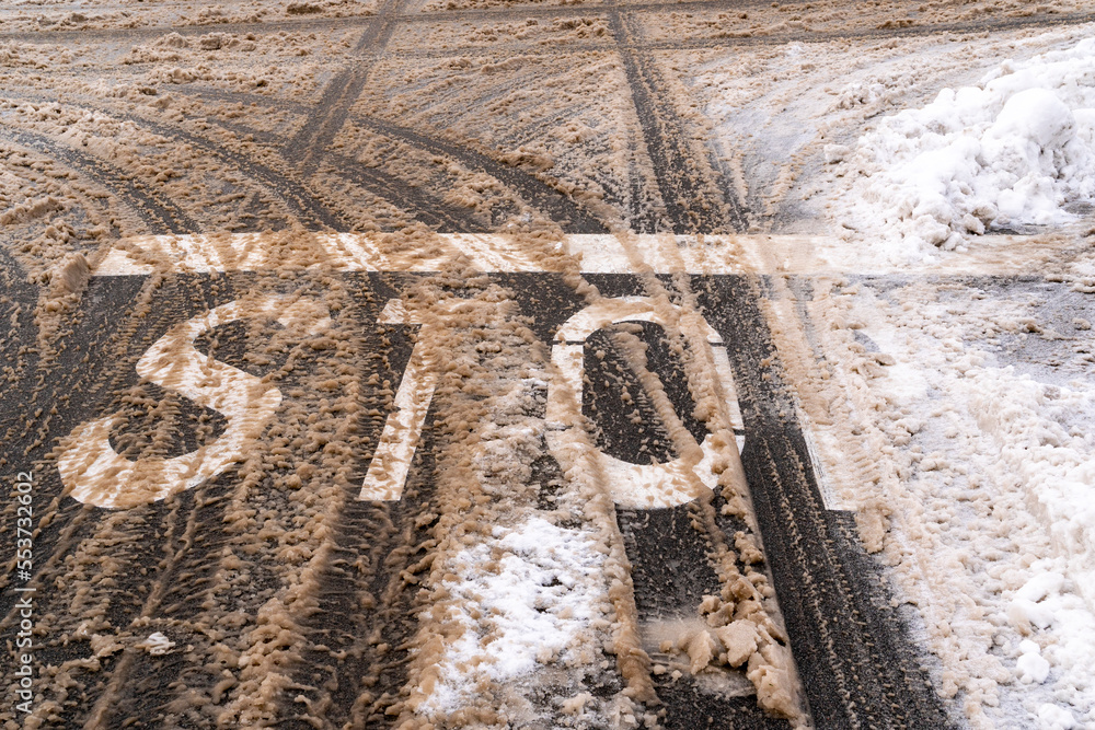 Winter road with STOP sign and car tracks in dirty snow and de-icing ...