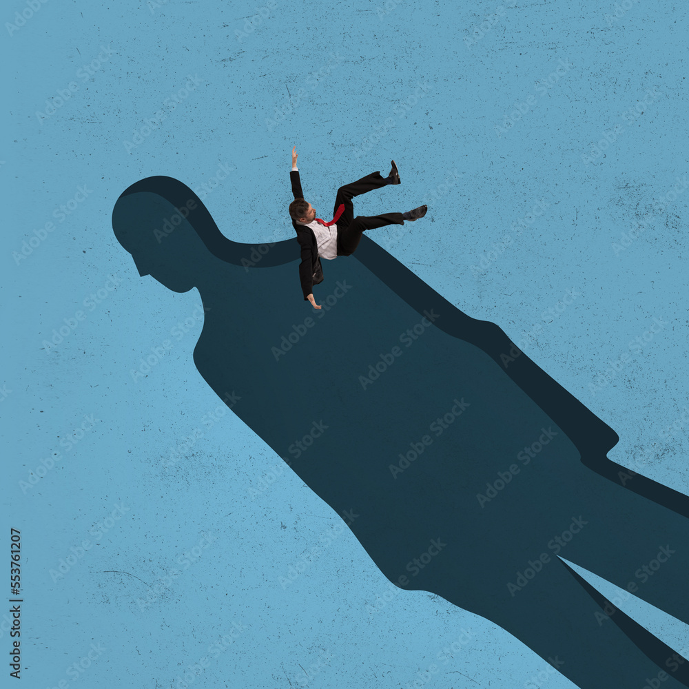 Young business man falling down over blue background with huge male ...
