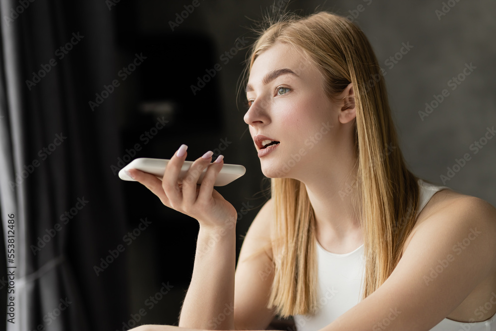 Blonde woman recording voice message on smartphone at home. Stock Photo ...