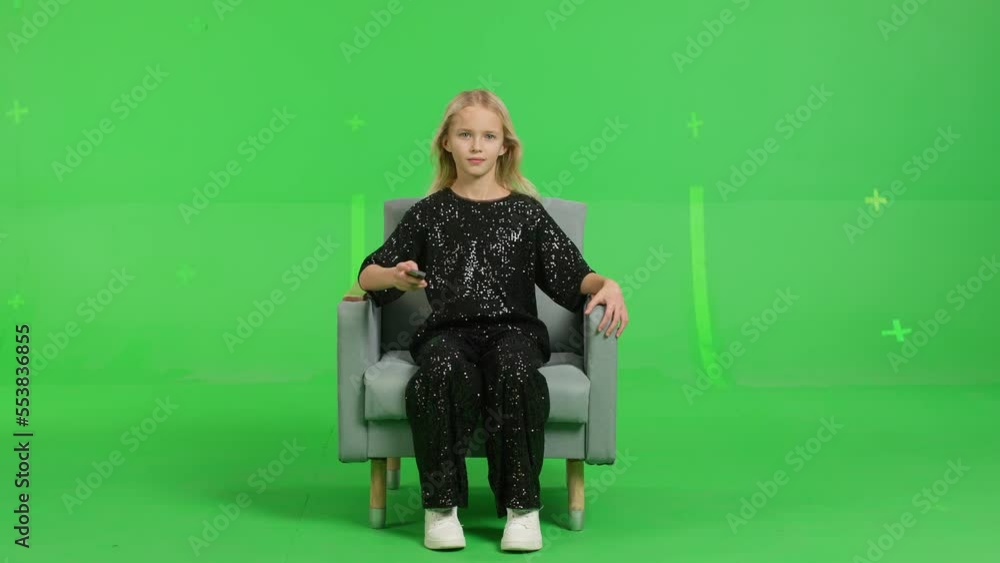 Young girl sitting in front of TV screen in an armchair with a remote ...