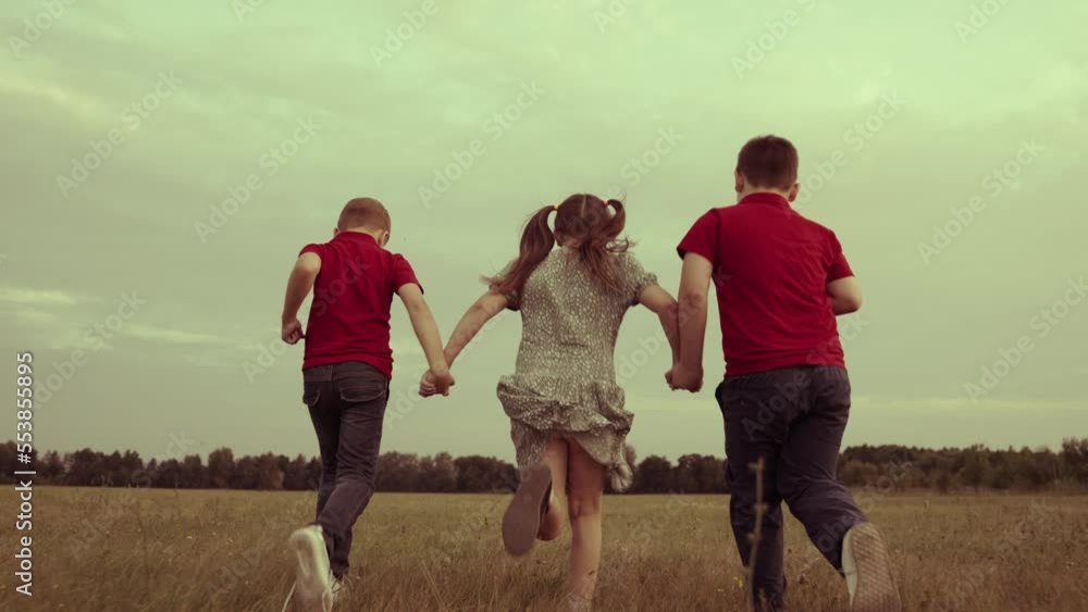 schoolchildren run holding hands green grass park. happy family ...