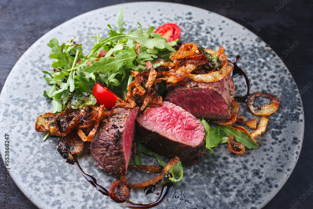 Gebratenes Angus Sirloin Rindssteak mit Zwiebelringen, Rucola Salat und ...