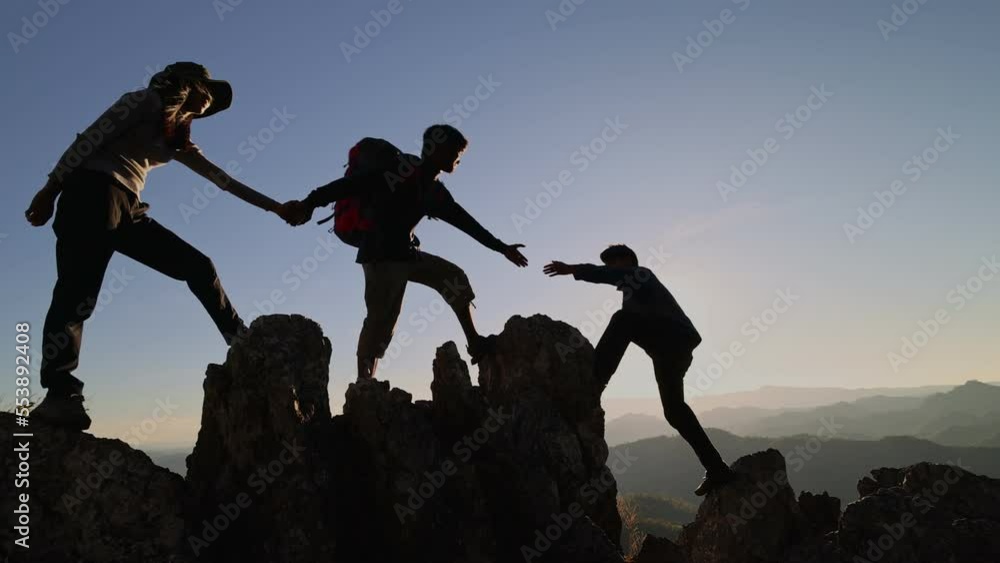 Silhouette of Group team tourists lends helping hand climb cliffs ...