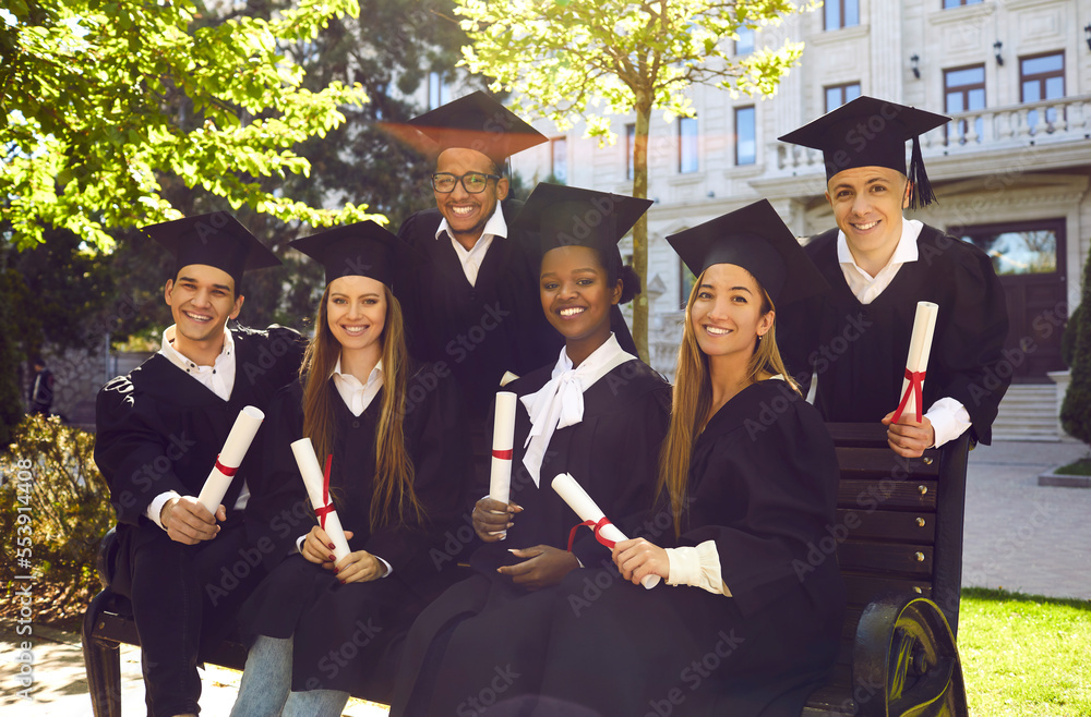 Happy, smiling diverse graduates outside college or university building ...