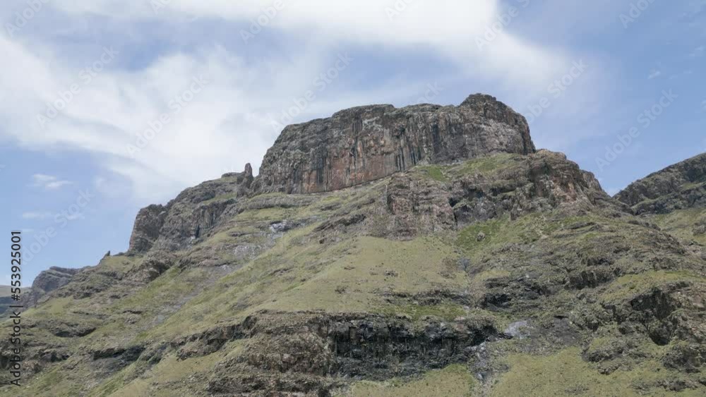Steep ancient stone escarpment rises above green highland meadow Stock ...
