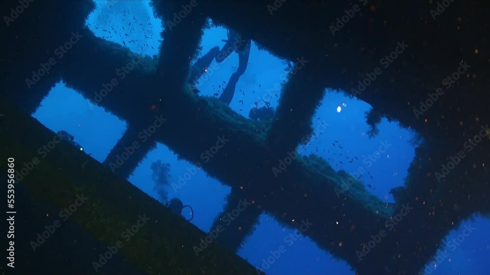 Scuba divers swimming over ship wreck filmed underwater from inside ...