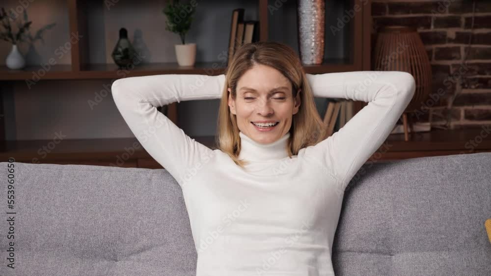 Contented attractive young woman relaxing on sofa, taking deep breath ...