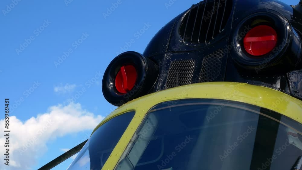 An outside view of the cockpit of a yellow helicopter and black engines ...