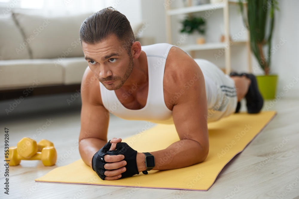Man sports home training on the floor on a mat with dumbbells ...