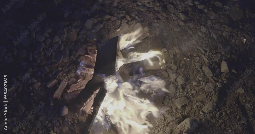 Wind blowing over a burning camping bone fire from above scene in slow ...