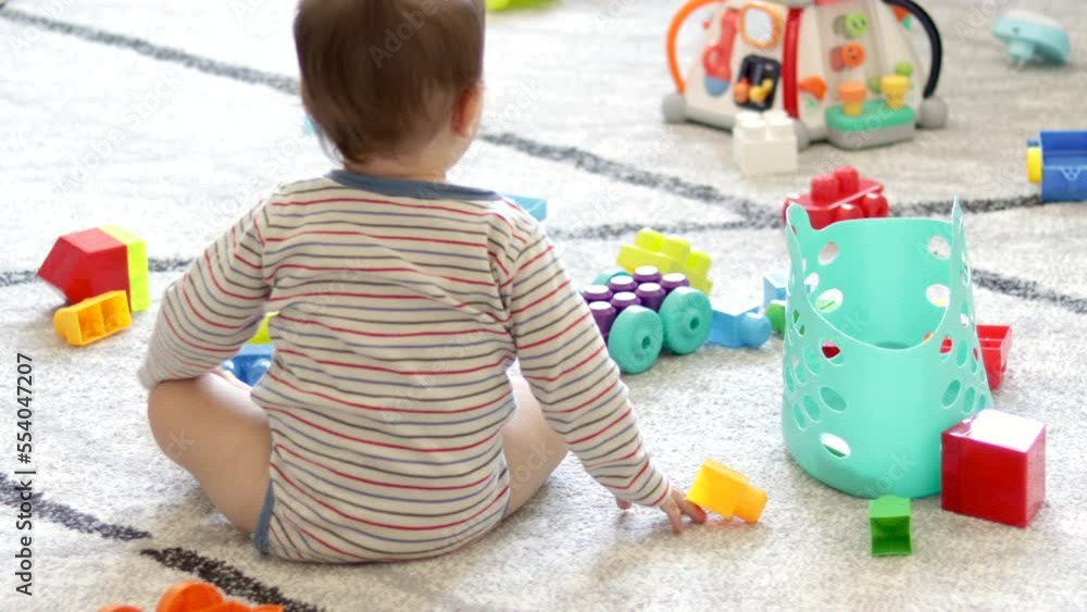 baby boy playing with toys sitting on floor carpet mess in house home ...