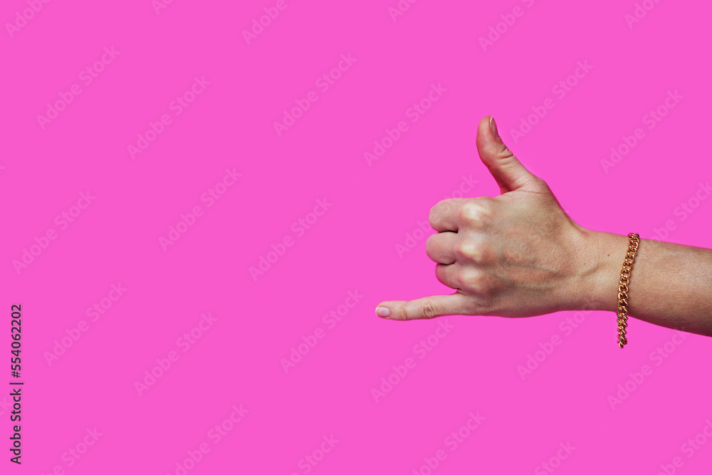 Hand gesture Shaka sign against pink background, gold chain on wrist ...