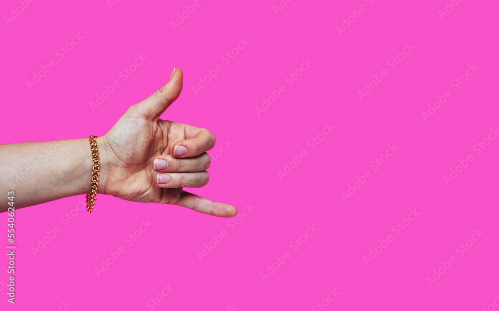 Hand gesture Shaka sign against pink background, gold chain on wrist ...