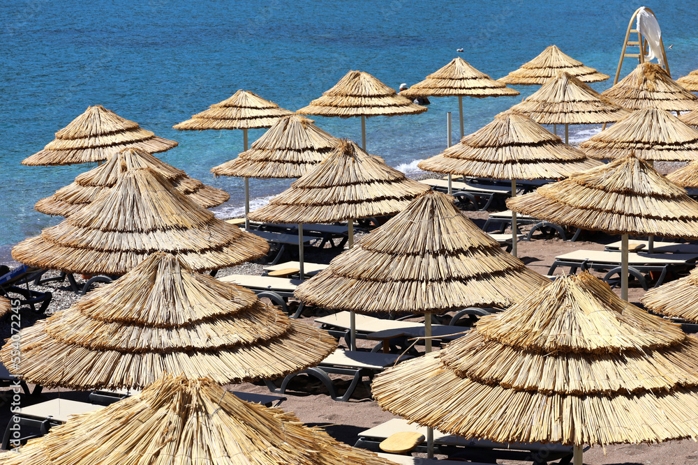 Sea beach with wicker parasols and lounge chairs. Picturesque view to ...