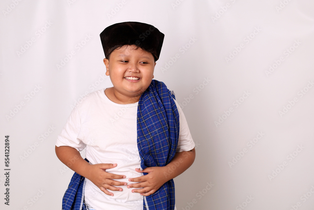 Asian boy feel very full after eating too much food. The boy holds his ...