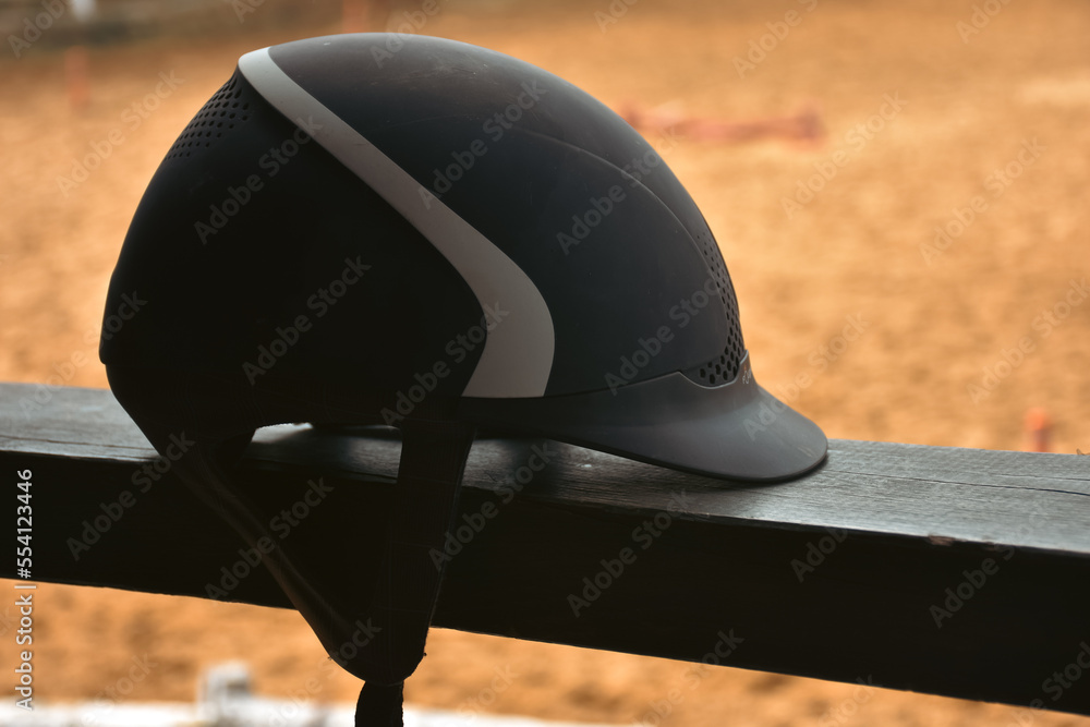 Close up view of black Equestrian helmet with blurred horse farm view ...