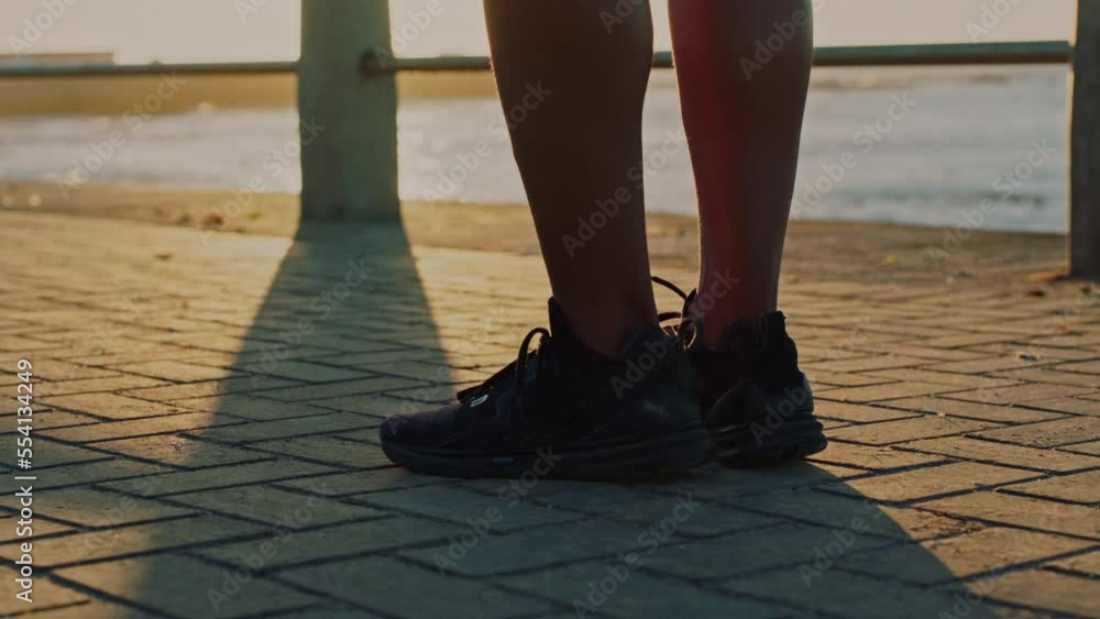 Fitness, shoes and man stretching feet for running on beach promenade ...