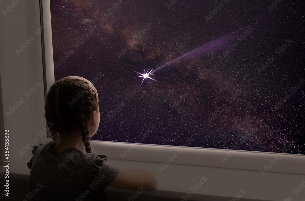 Little girl near window looking at shooting star in beautiful night sky ...