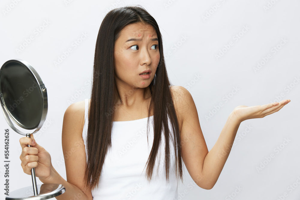 Asian woman with mirror in hand facial skin problems, acne and ...