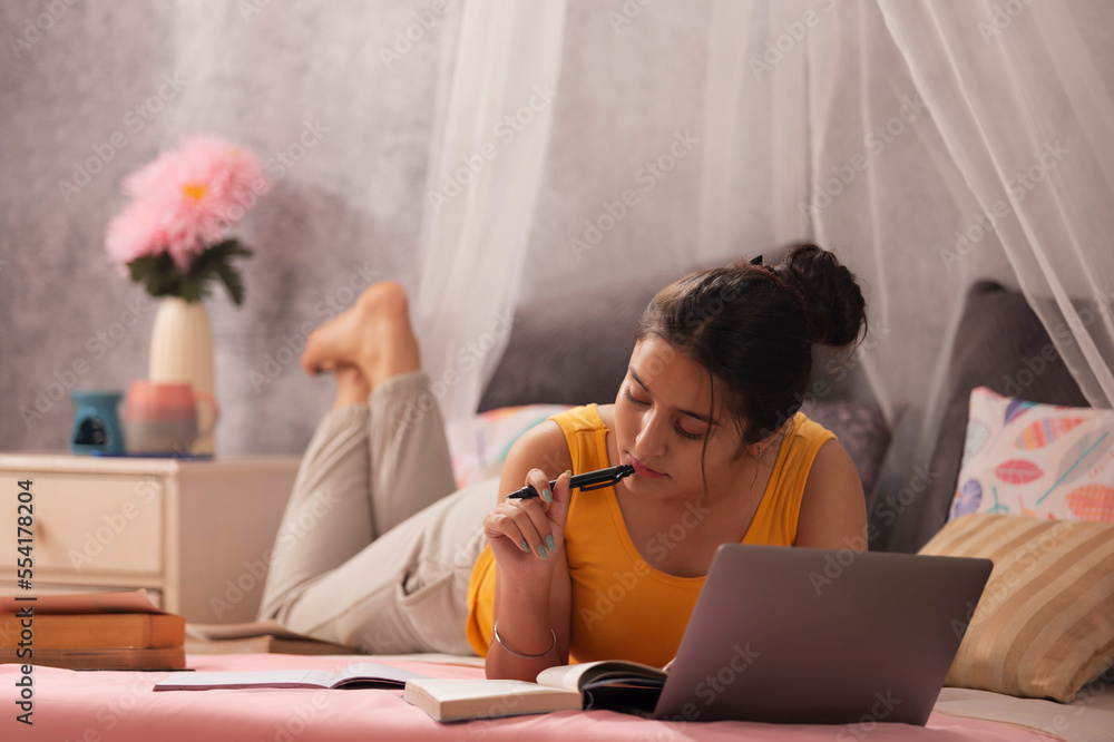 Teenage girl lying on bed and studying with laptop Stock Photo | Adobe ...