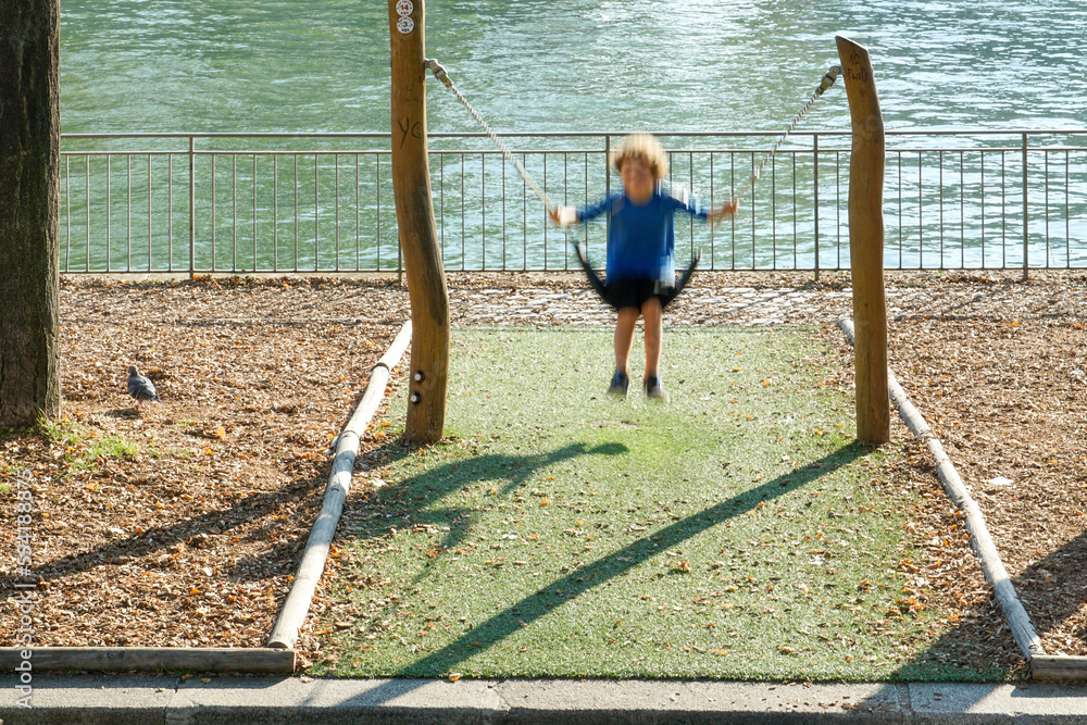 Paris, France - A young boy swinging on a swing set on the banks of the ...
