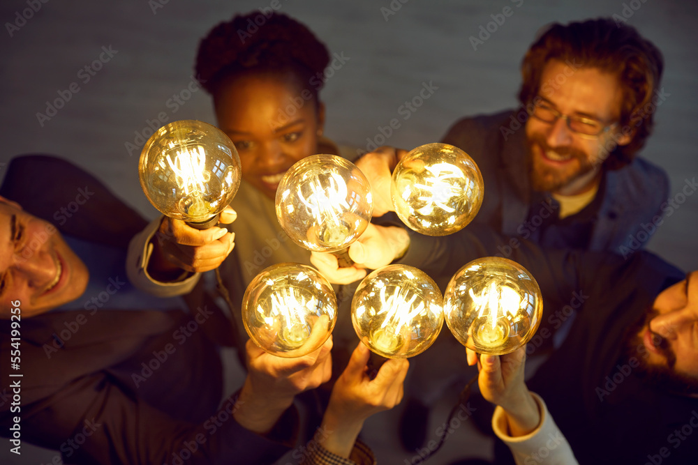 Team work. Bright glowing light bulbs in hands of various people as ...
