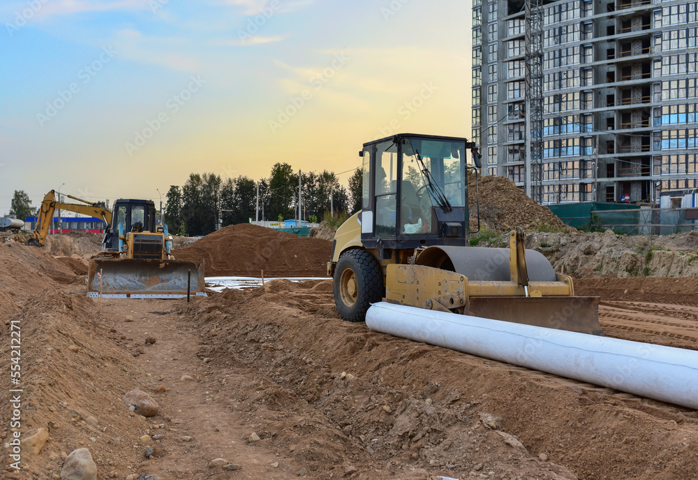 Road construction using road machinery. Soil compactor and dozer at ...