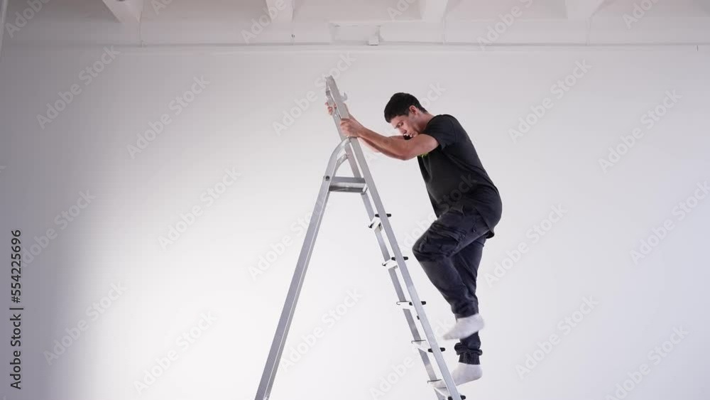 Unlucky male maintenance worker climbs a ladder with a wrench and loses ...