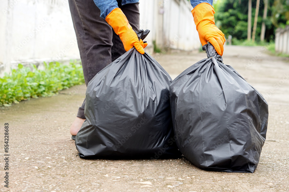 Closeup man holds black plastic bag that contains garbage inside ...